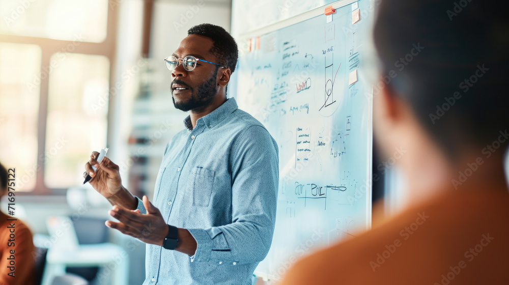 Man presenting or explaining something in front of a whiteboard with ...