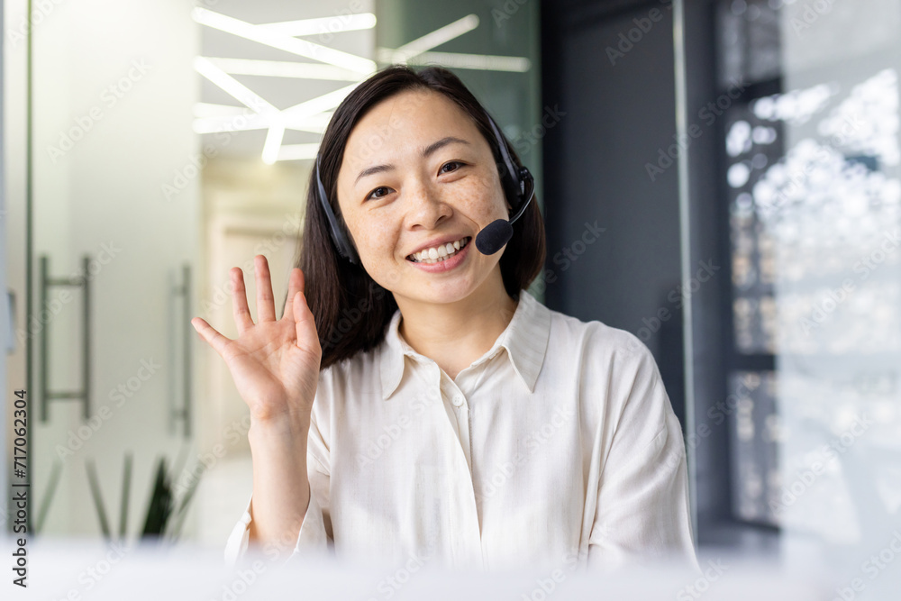 First person view of smiling asian woman in wireless headset with micro ...
