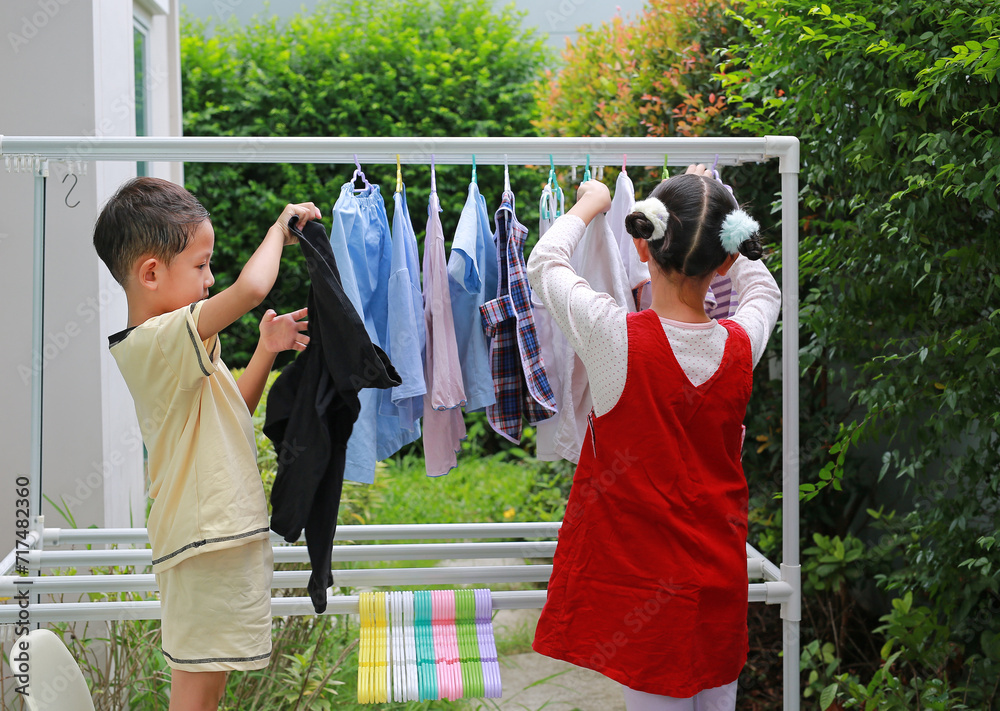 Portrait of Asian girl and boy helping to do dry the clothes at garden ...