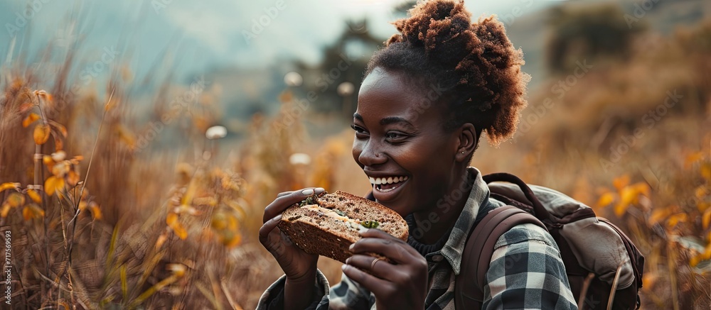 Happy young african woman eating sandwich and smiling Taking break ...