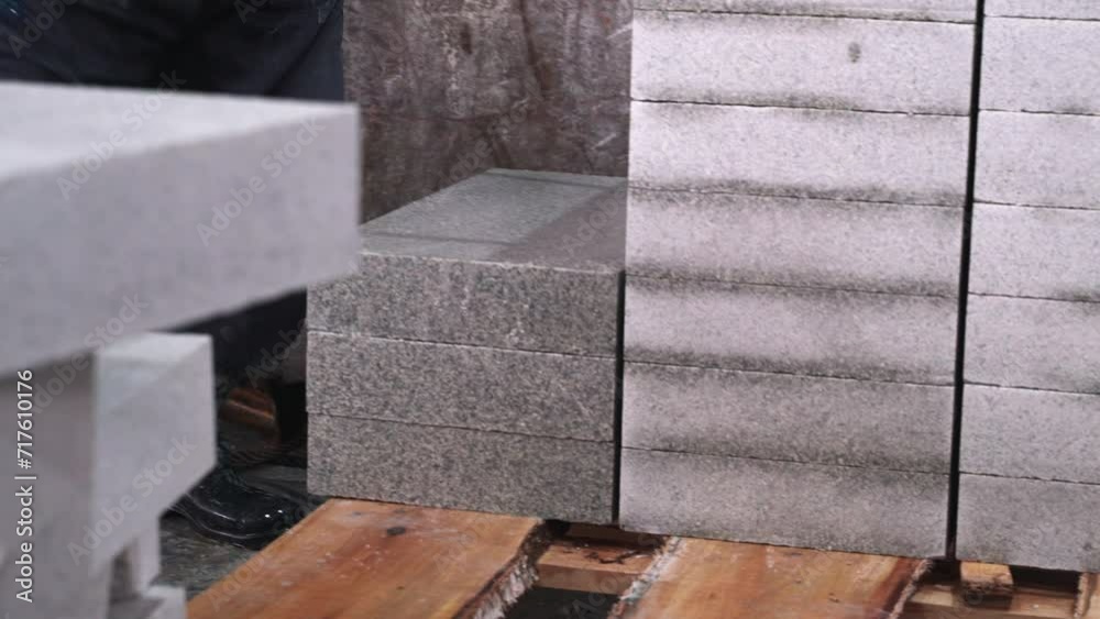 Worker is putting processed granite stone slabs in a pile at the ...