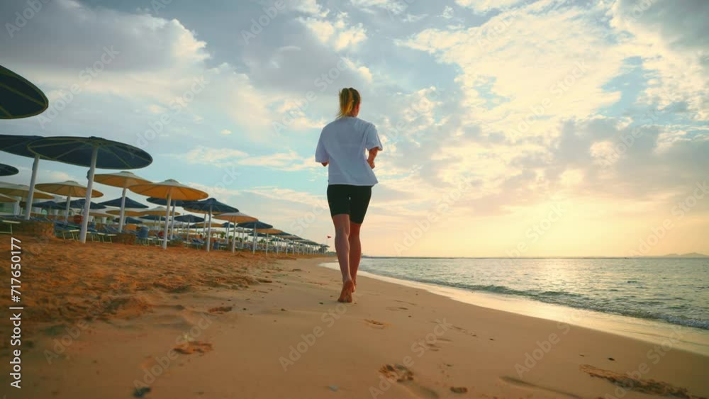 Woman jogging running on sea beach. Barefooted woman runs along sandy ...