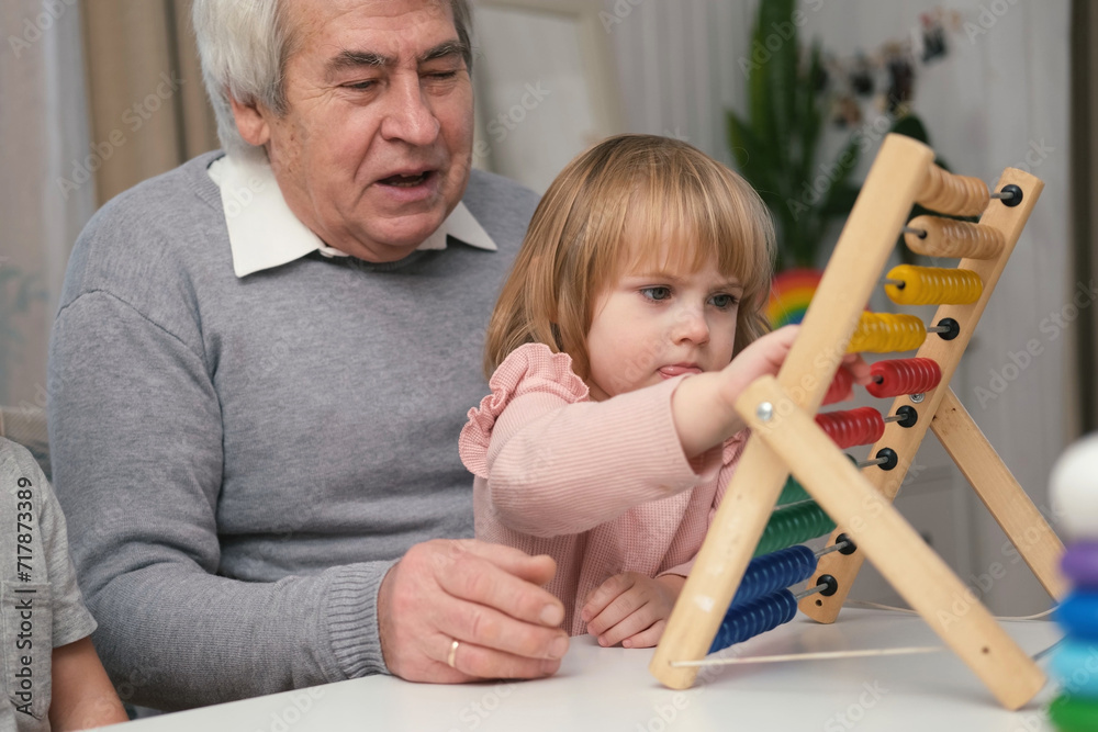 Grandfather playing toys with grandson and young granddaughter indoor ...