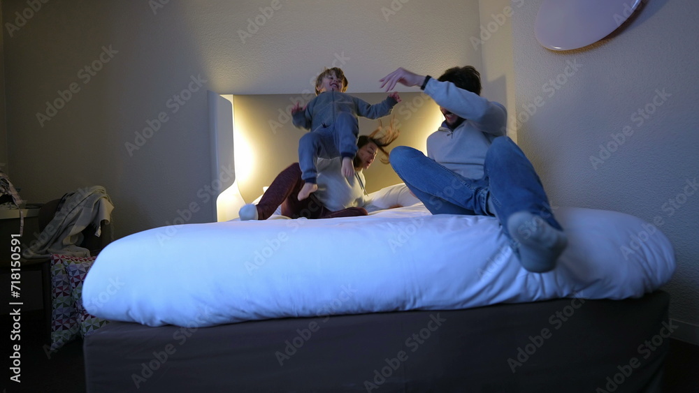 Happy carefree parents falling into bed with their little 3 year old ...