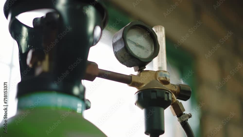 Green gas cylinder with valve and pressure regulator in workshop of ...