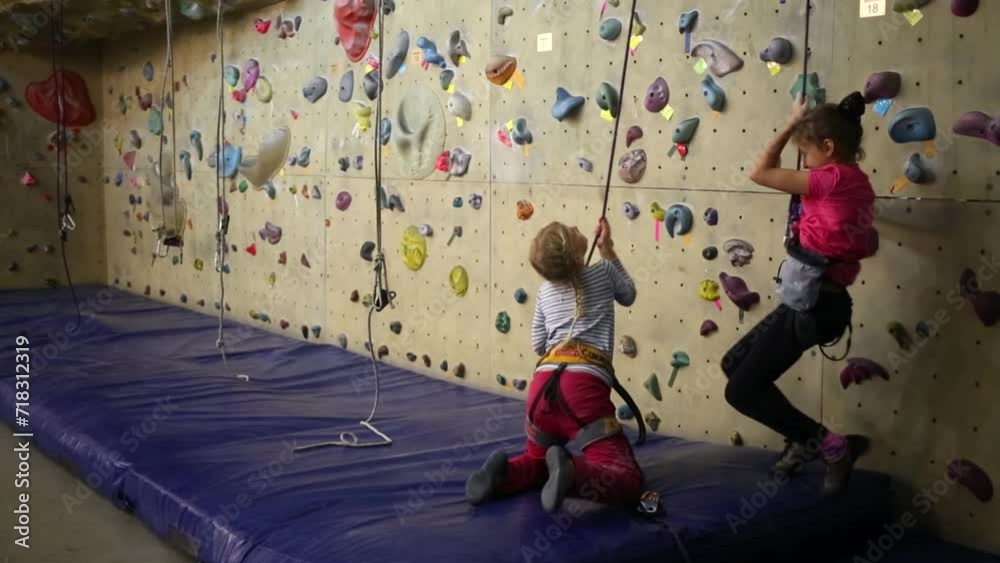 Two girls in the climbing gym trying to raise one of them on a rope ...