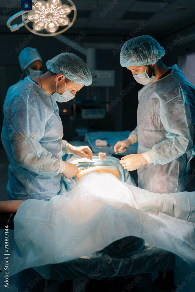 Vertical portrait of concentrated males surgeons with female assistant ...