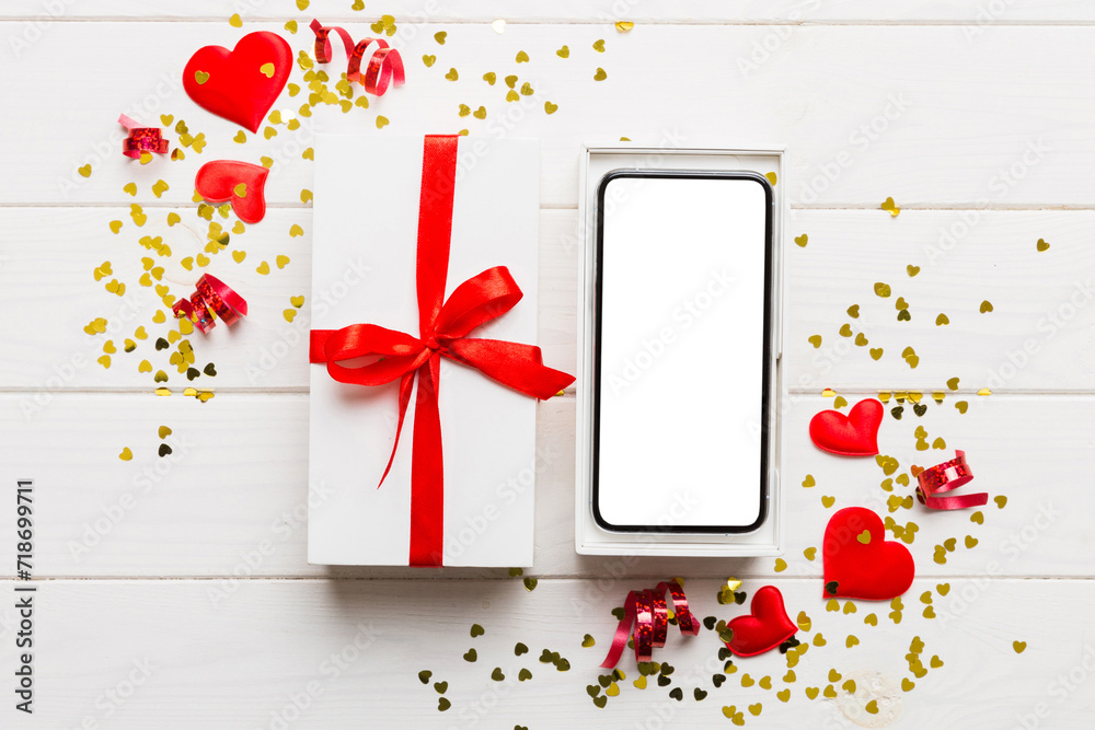 Opened gift box with ribbon and phone on color background, top view ...