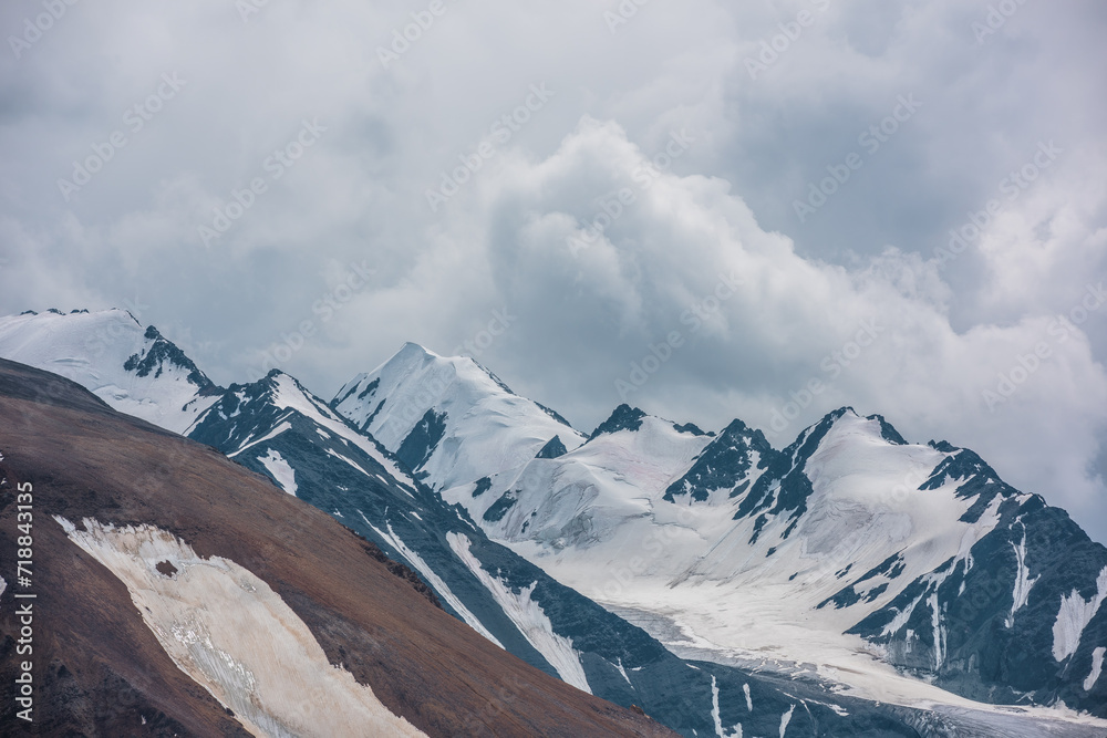 Dramatic view to large rock mountain range with snow-capped pinnacle in ...