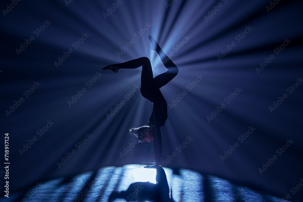 Female gymnast on dark background of studio with backlight. Acrobatic ...