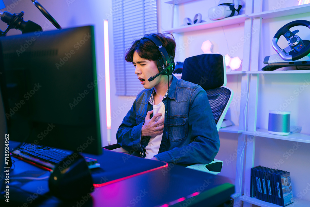 Young Asian man professional gamer wearing a jeans jacket sits on a ...