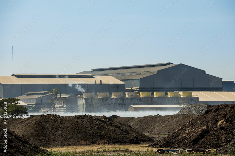 Pile of sugar cane waste in front of factory. Toxic smoke from ...