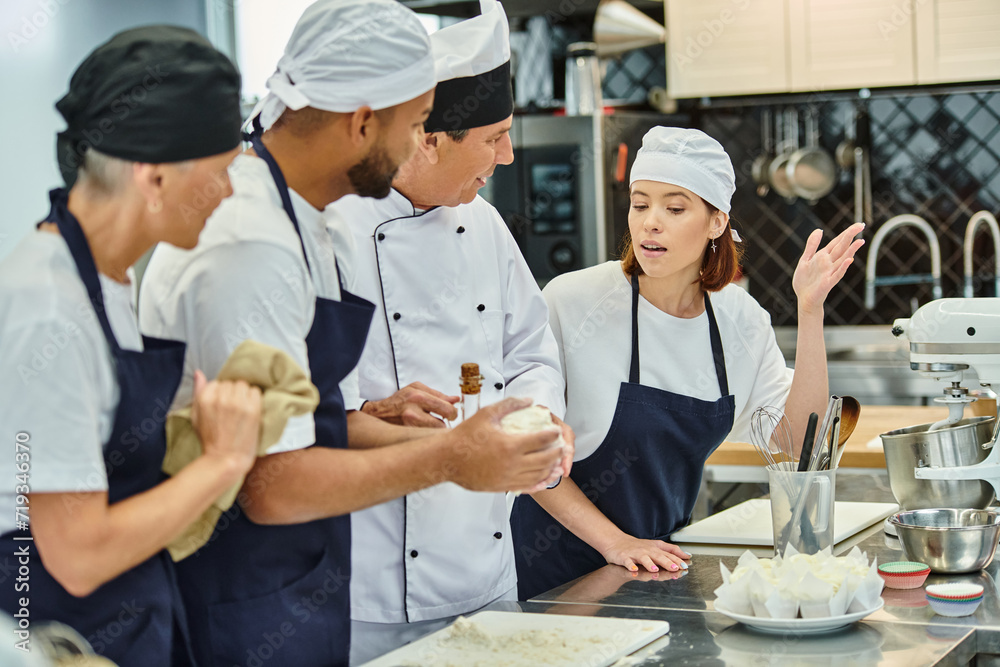 jolly chief cook in white hat smiling at his young chef asking question ...