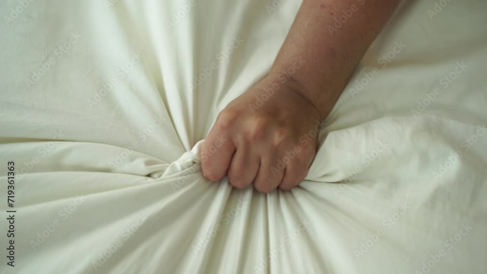 Middle age woman hand tight clutches sheet on bed. The concept of ...