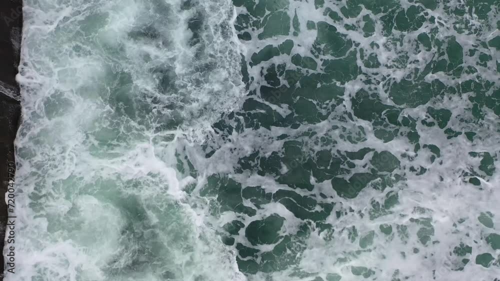 Тop view from drone above of foamy sea waves crashing into a pier with ...