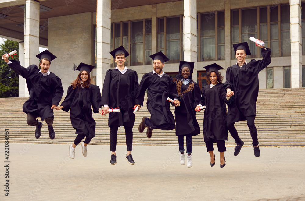 Happy smiling graduates students classmates jumping in black graduate ...