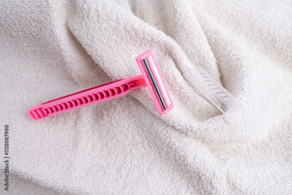 Women's razor with a towel on a light background. Removing unwanted ...