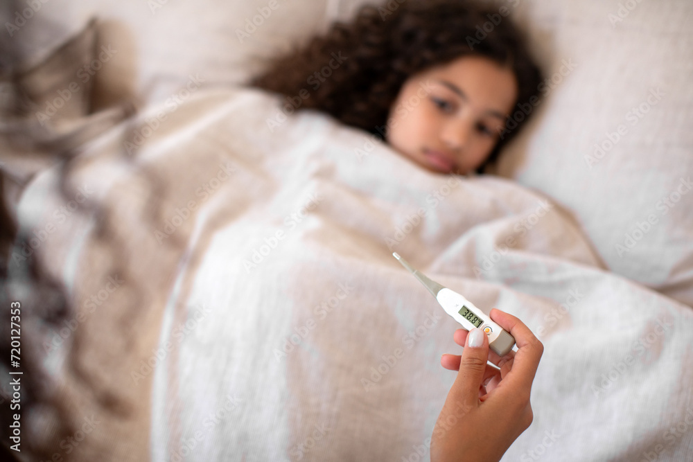Mother holding digital thermometer with high temperature for check health of her daughter, sick ...