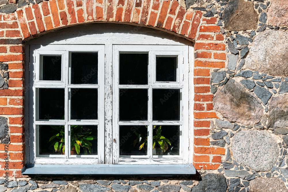 Window with a frame covered with old weathered paint, on a stone wall ...