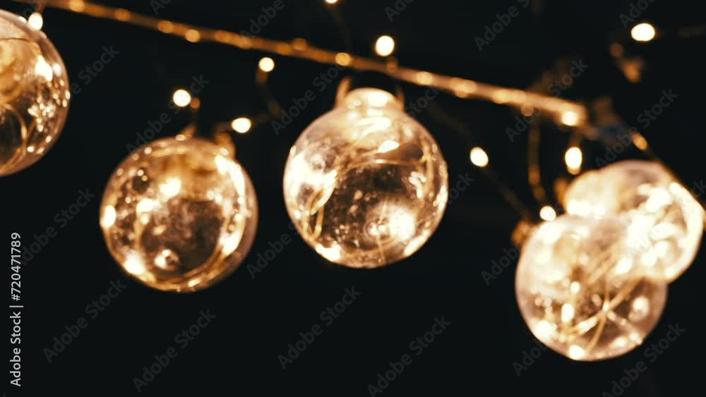 Lots Hanging Glowing Vintage Edison Light Bulbs on Black Background. Bottom view. Warm light ...
