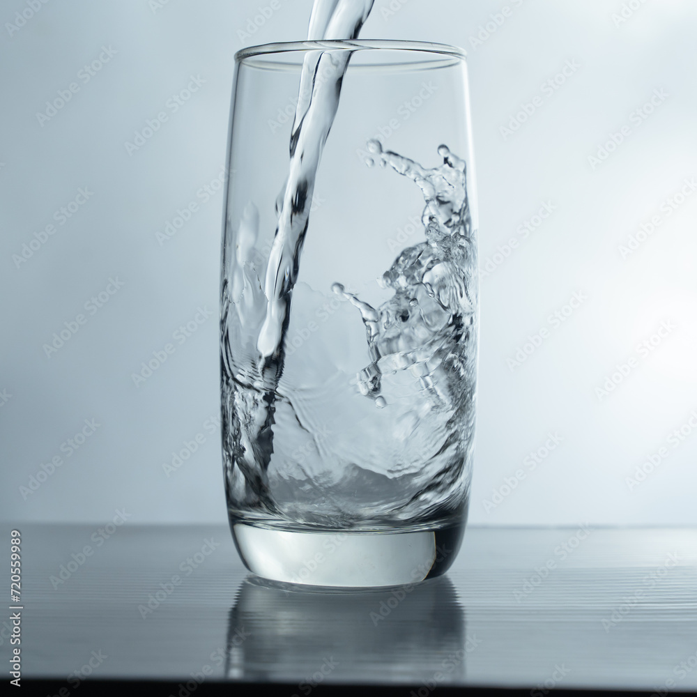 pouring water into glass on table, glass of water with splash isolated ...