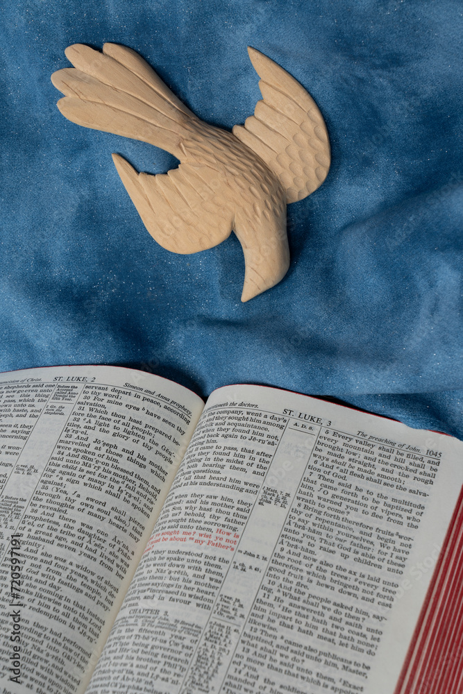 Holy Spirit figure descends on open Bible reading of St Luke. The dove ...