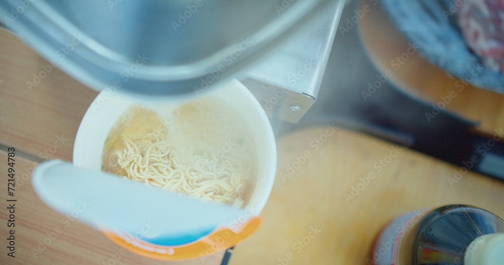 Overhead view of instant noodles being prepared with steaming hot water ...