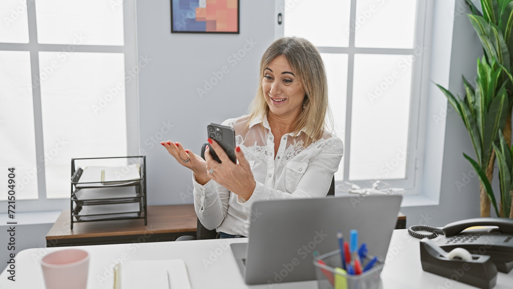 Caucasian woman using smartphone in modern office interior setting ...