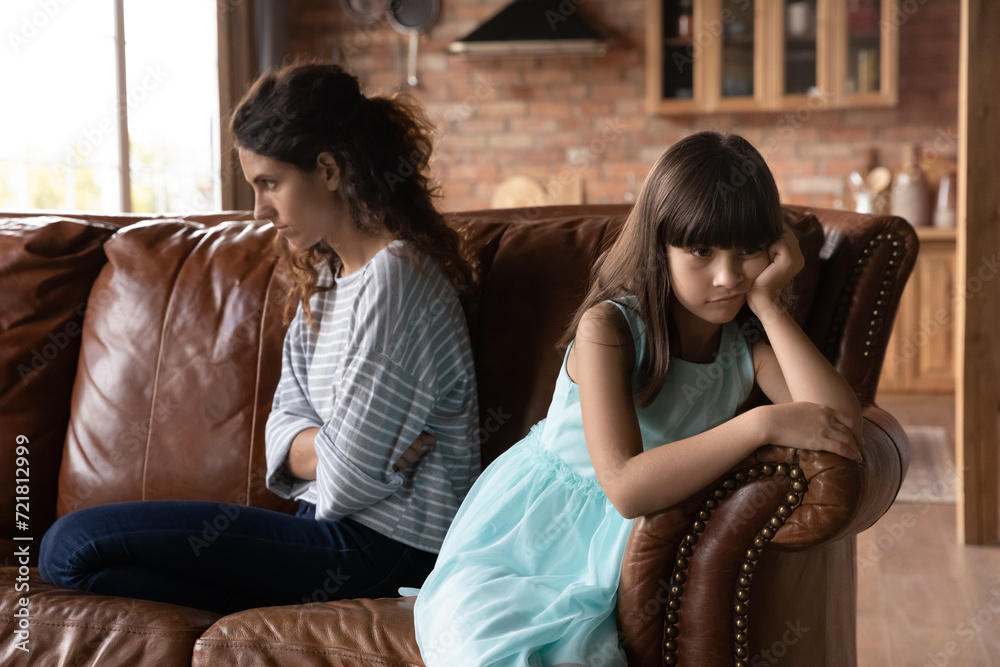 Misunderstanding. Upset offended young latin mother and preteen child daughter girl sit on couch ...