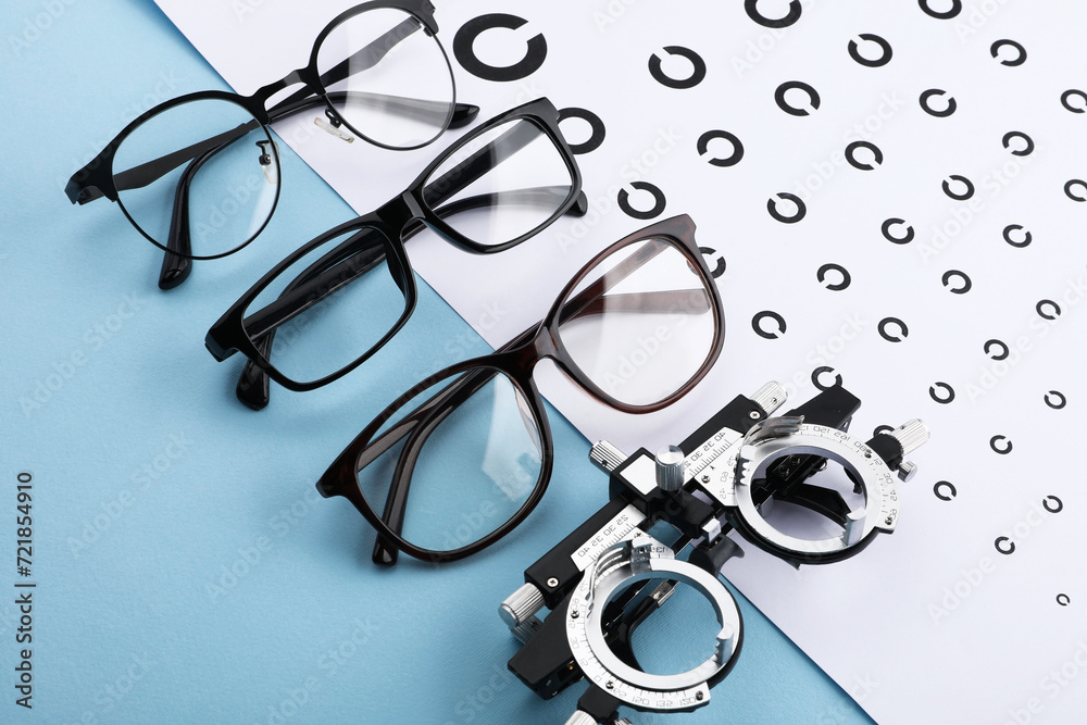 Vision test chart, glasses and trial frame on light blue background ...