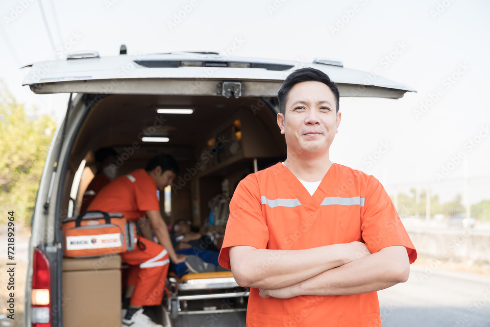 Asian male ambulance staff member standing with crossed arms. He is ...