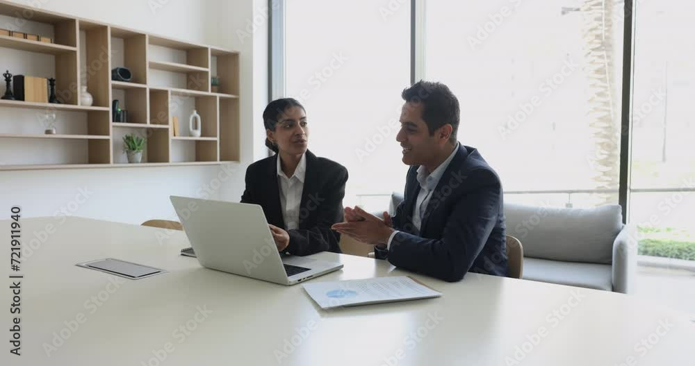Couple of Indian coworkers talking at large white meeting table ...