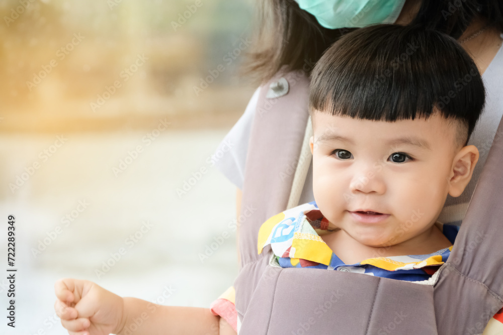 Asian baby toddler with his mother in the ergo carrier on the sunset ...