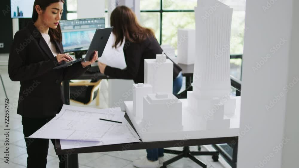 Asian contractor takes notes about 3d printed model on laptop ...