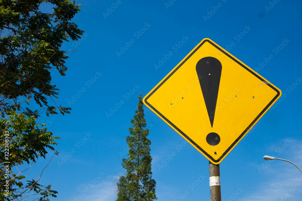 Warning sign with exclamation mark isolated on a blue sky with clouds ...
