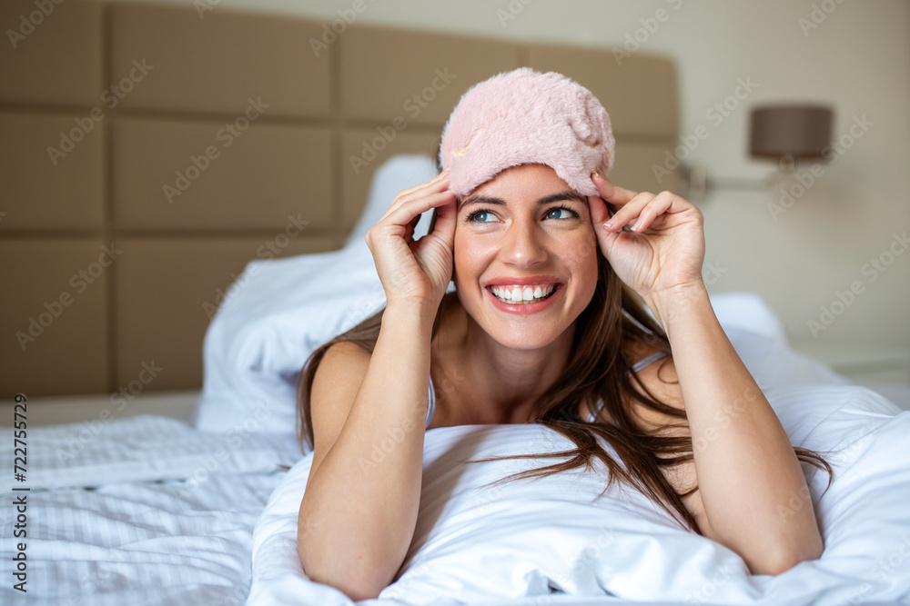 Beautiful excited girl in sleeping eye mask lying in bed. Close up face ...