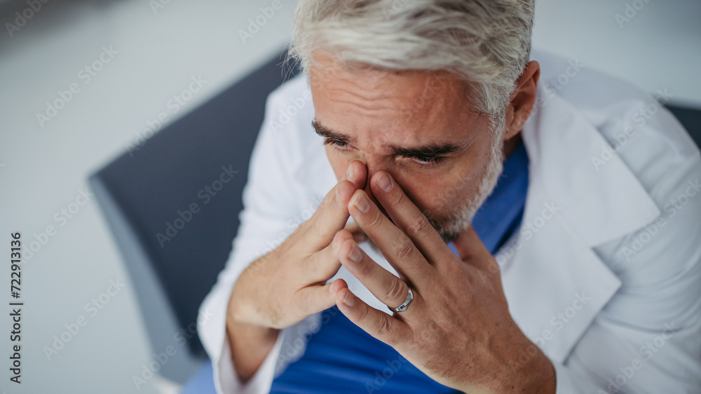 Portrait of frustrated, exhausted doctor sitting in hospital corridor ...