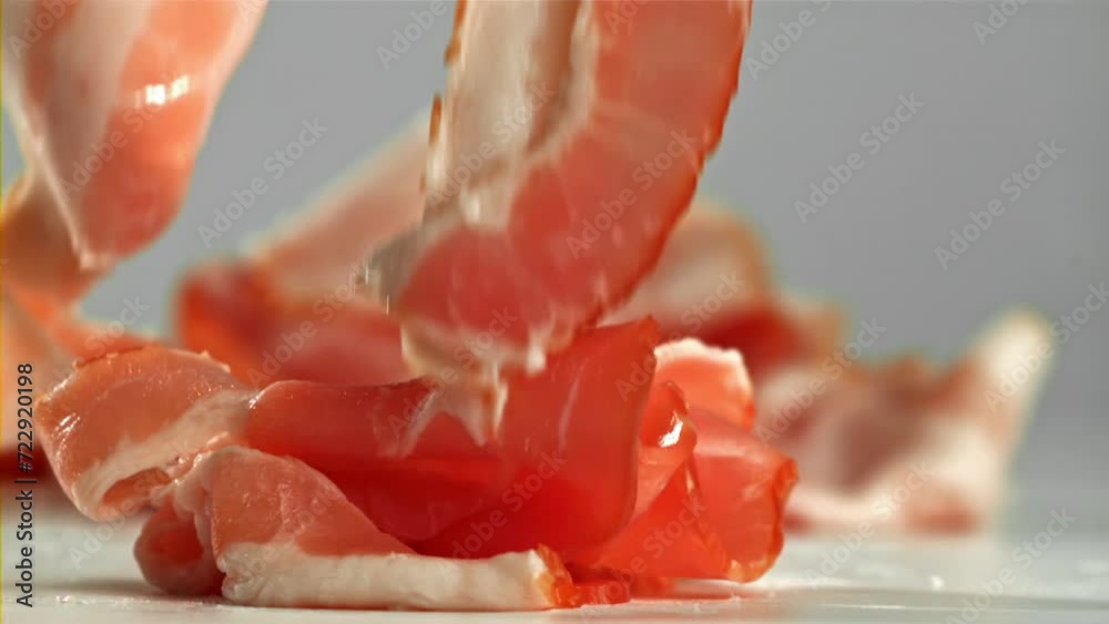 Bacon falling on white background. Filmed on a high-speed camera at ...