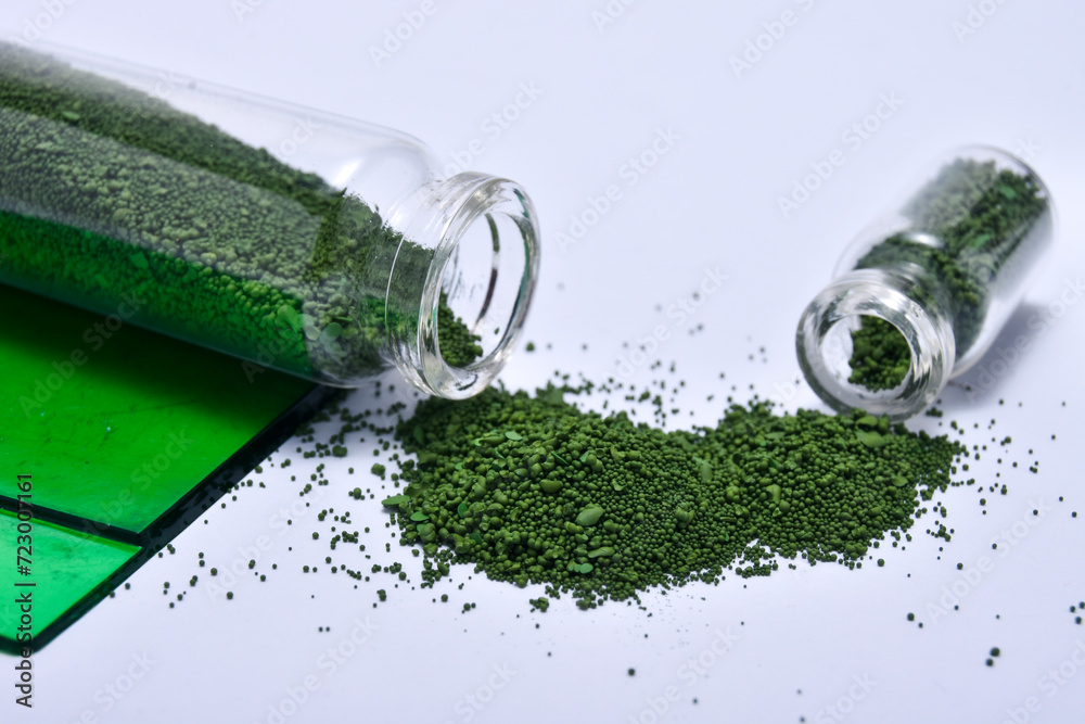 green masterbatch powder spilled from a glass bottle and isolated on a ...