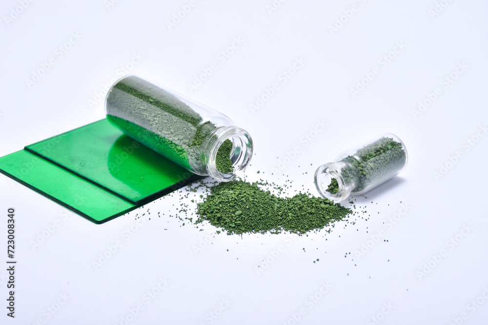 green masterbatch powder spilled from a glass bottle and isolated on a ...