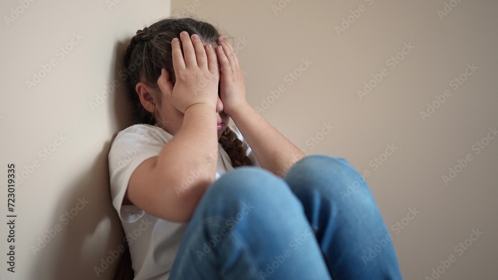 sad girl sitting in the corner crying a covered her face with her hands ...