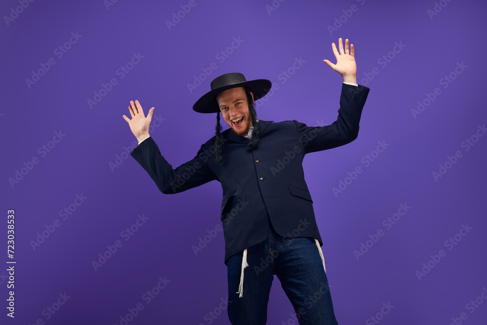 Happy and excited young Jewish man with sidelocks in hat, costume ...