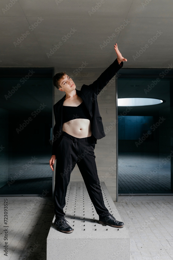 Trans young man wearing suit with arm raised standing in basement Stock ...