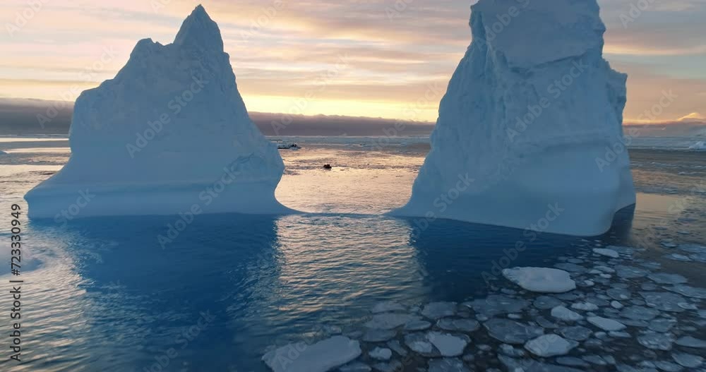 Two Antarctic melting icebergs in sunset landscape. Drone flight ...
