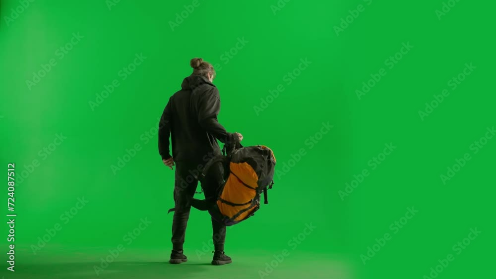 Rear view of a male traveler removing a backpack from his back, in a ...
