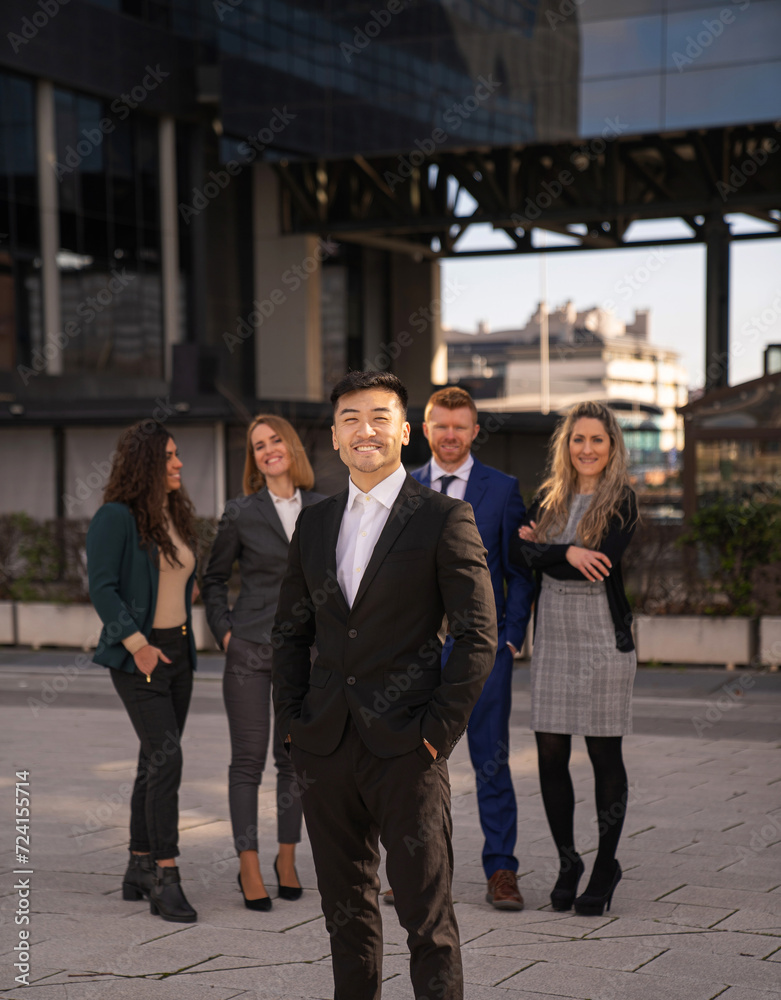 happy asian executive smiling with employees behind multiethnic group ...