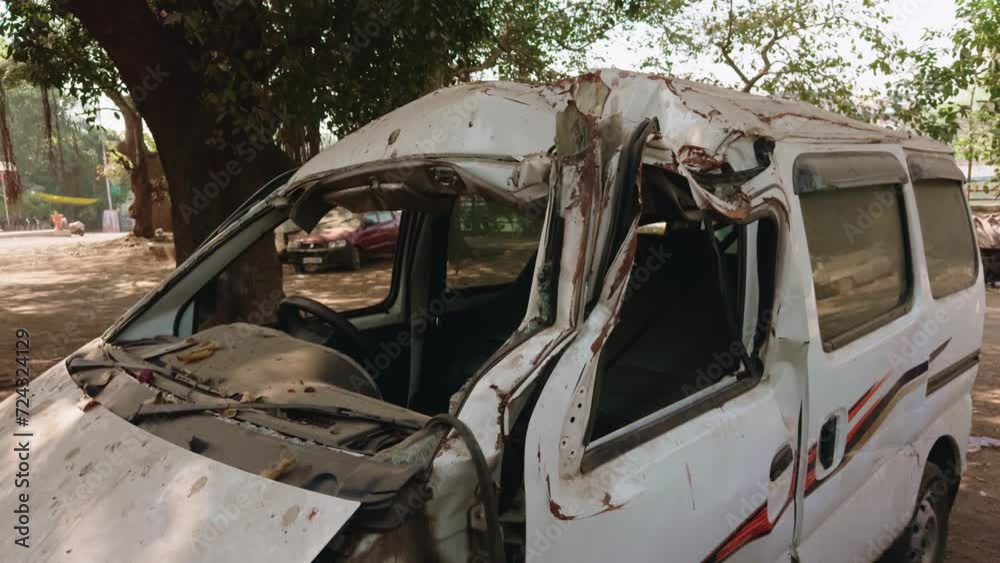 Wrecked white van with severe roof and body damage parked under a tree ...