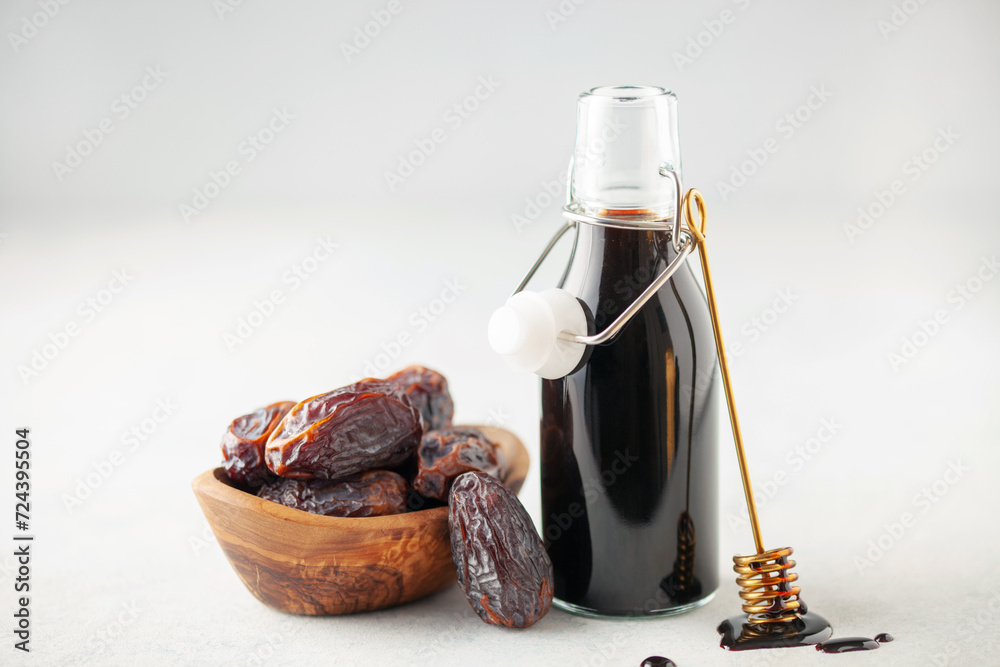 Natural dates syrup in bottle with whole dates in white background. Eco ...
