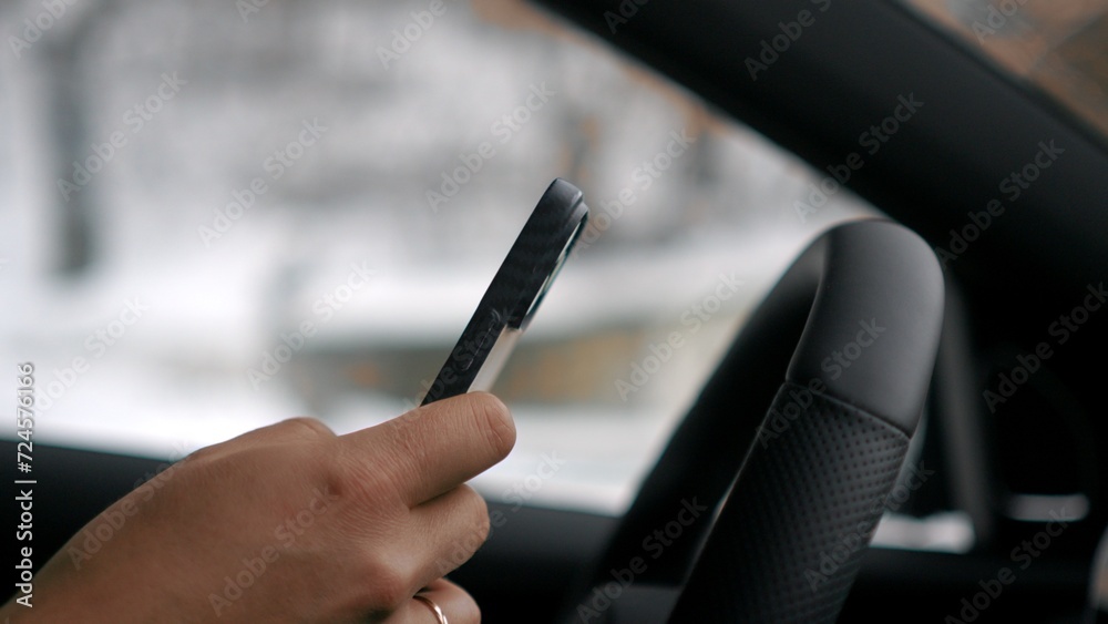 person sits behind the wheel of a car, holding a cell phone in their ...