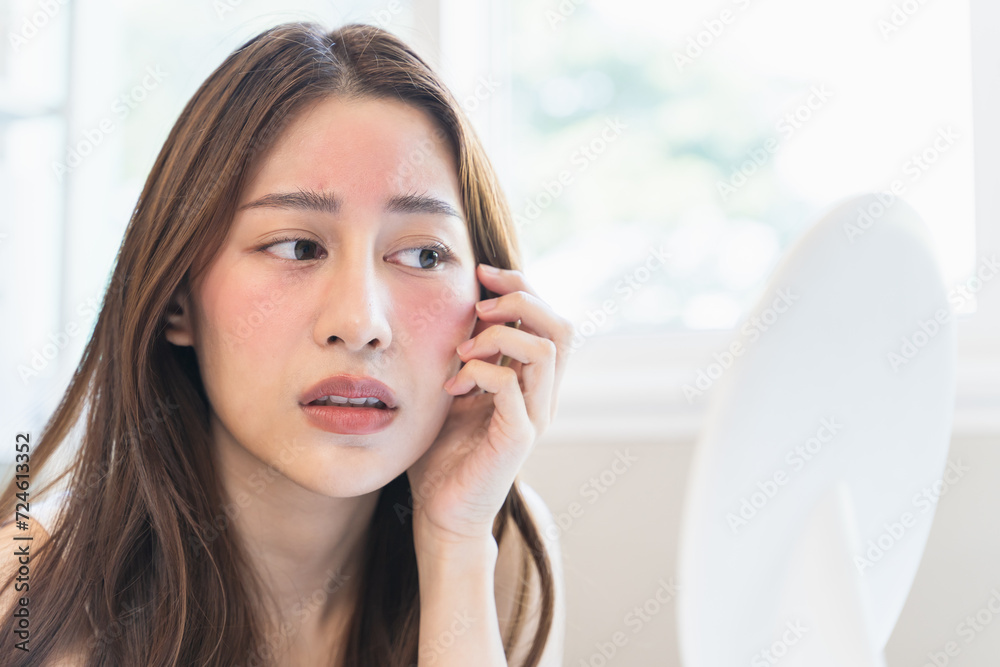 Asian young woman looking face skin in the mirror have a red rash on ...